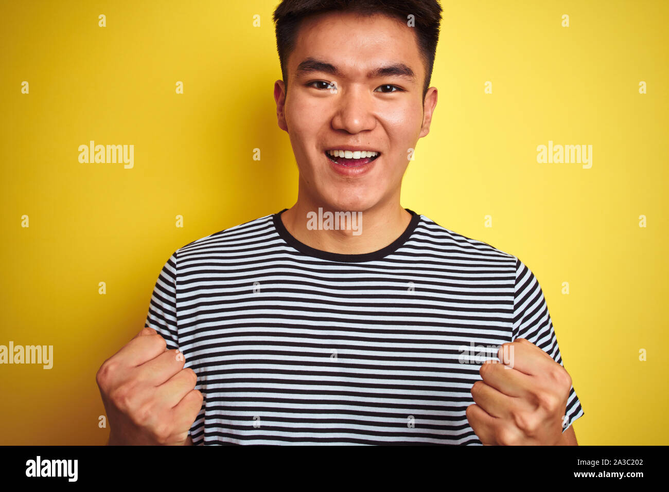 Young asian chinese man wearing striped t-shirt standing over isolated ...