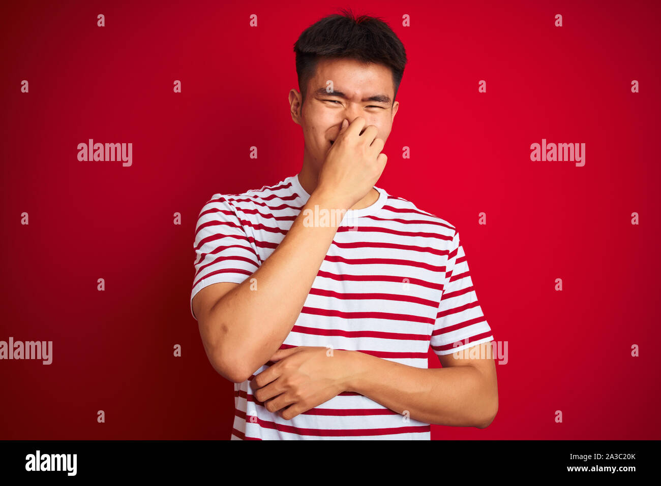 Young asian chinese man wearing striped t-shirt standing over isolated ...