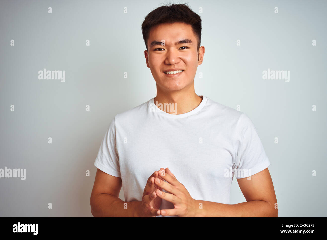 Young asian chinese man wearing t-shirt standing over isolated white ...