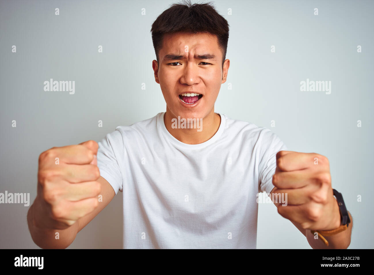 Young asian chinese man wearing t-shirt standing over isolated white ...