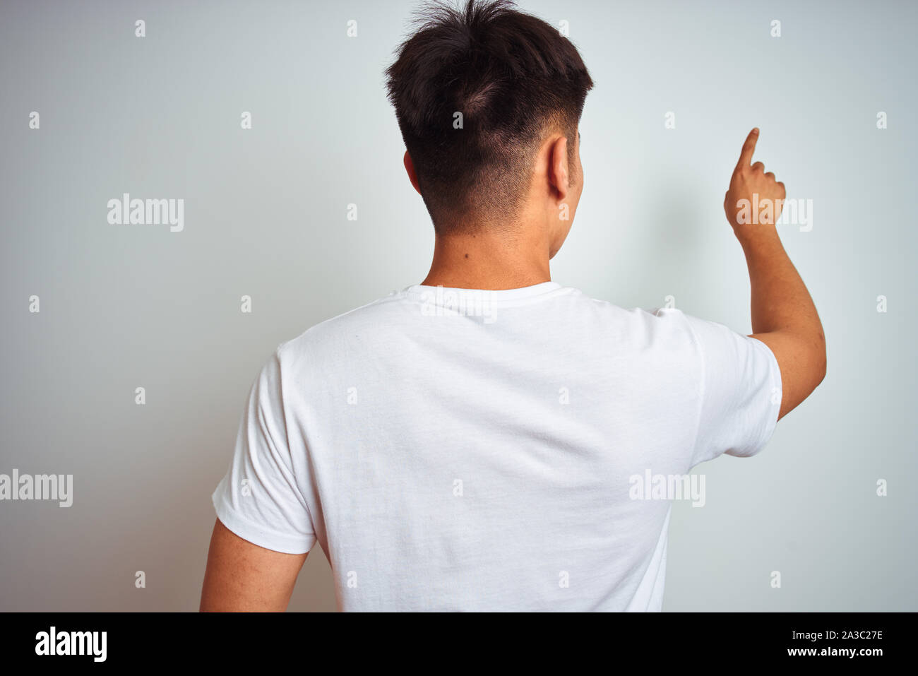 Young asian chinese man wearing t-shirt standing over isolated white ...