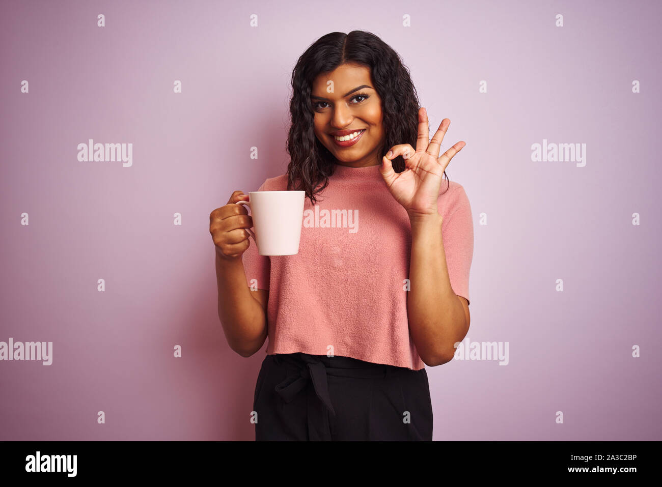 Transsexual transgender woman drinking cup of coffee over isolated pink ...
