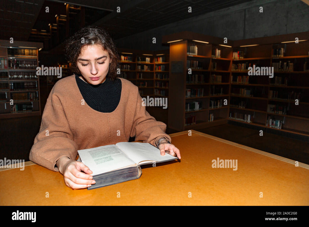 Young student girl reading book in library alone Stock Photo - Alamy