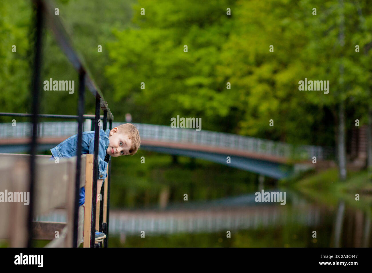 A little boy climbs a bridge railing in the park. The threat of ...