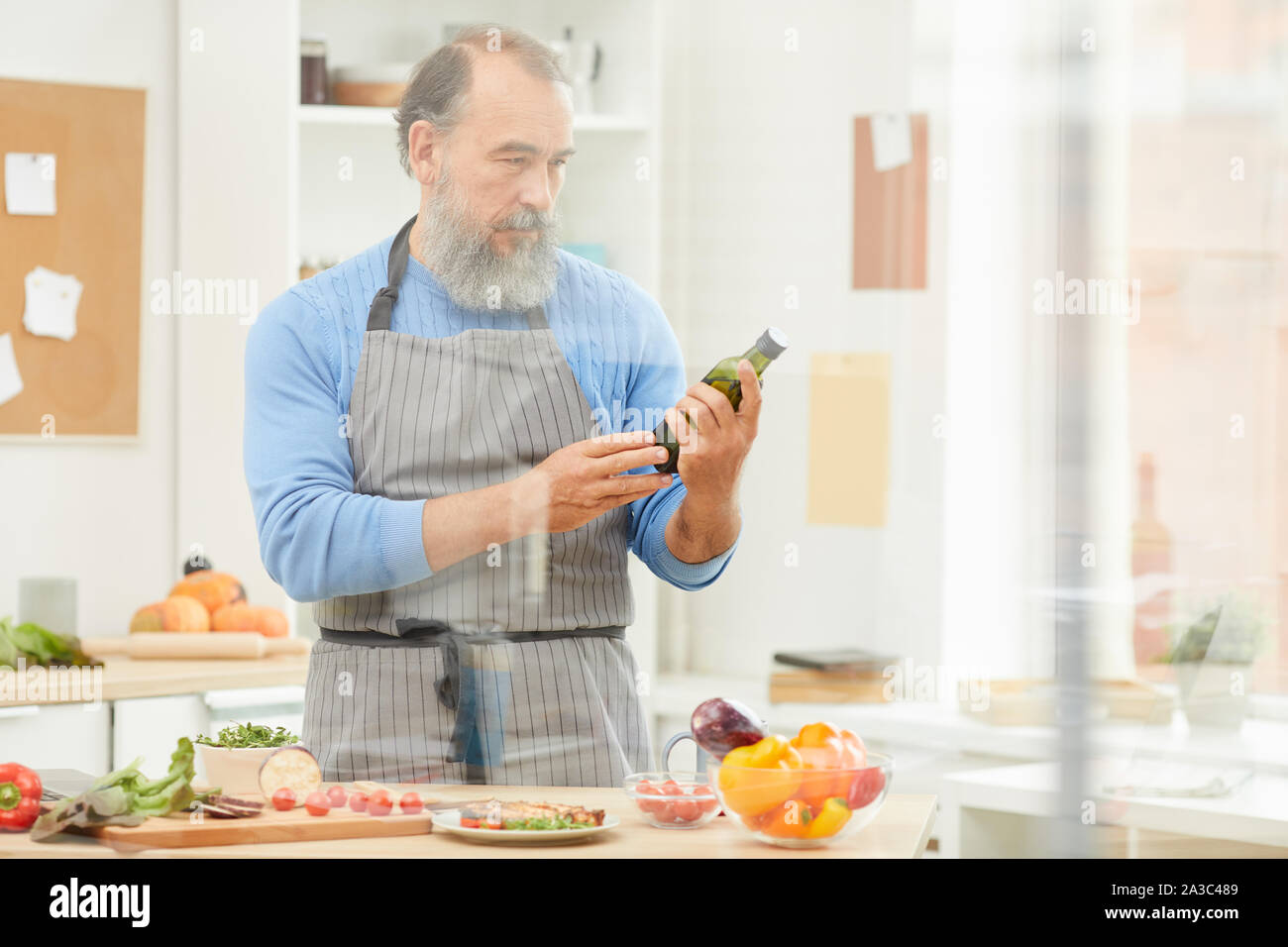 Waist up portrait of bearded senior man cooking dinner at home and ...