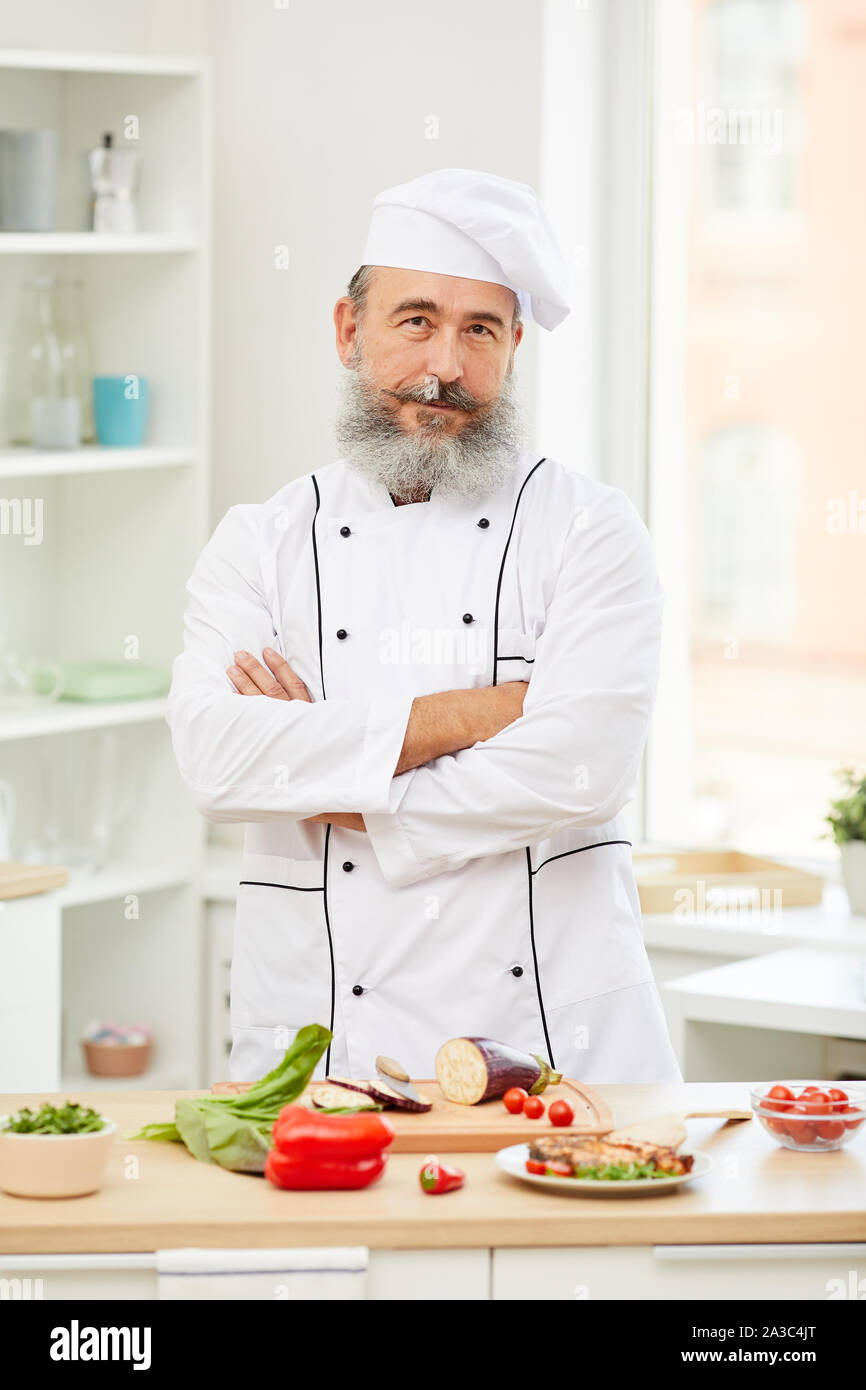 Waist up portrait of cheerful senior chef looking at camera standing ...