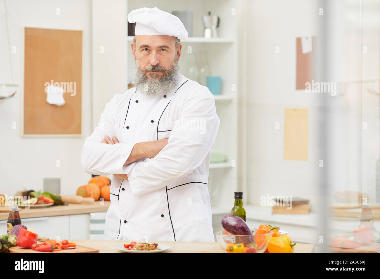 Waist up portrait of bearded senior chef posing confidently while ...