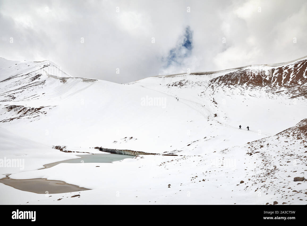 Tourist silhouettes are walking down the snow path at beautiful cloudy ...