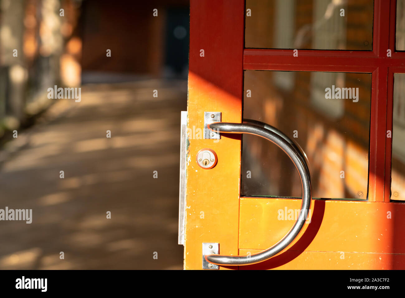 Curved steel handle on an open wooden door in sunlight in a close up ...