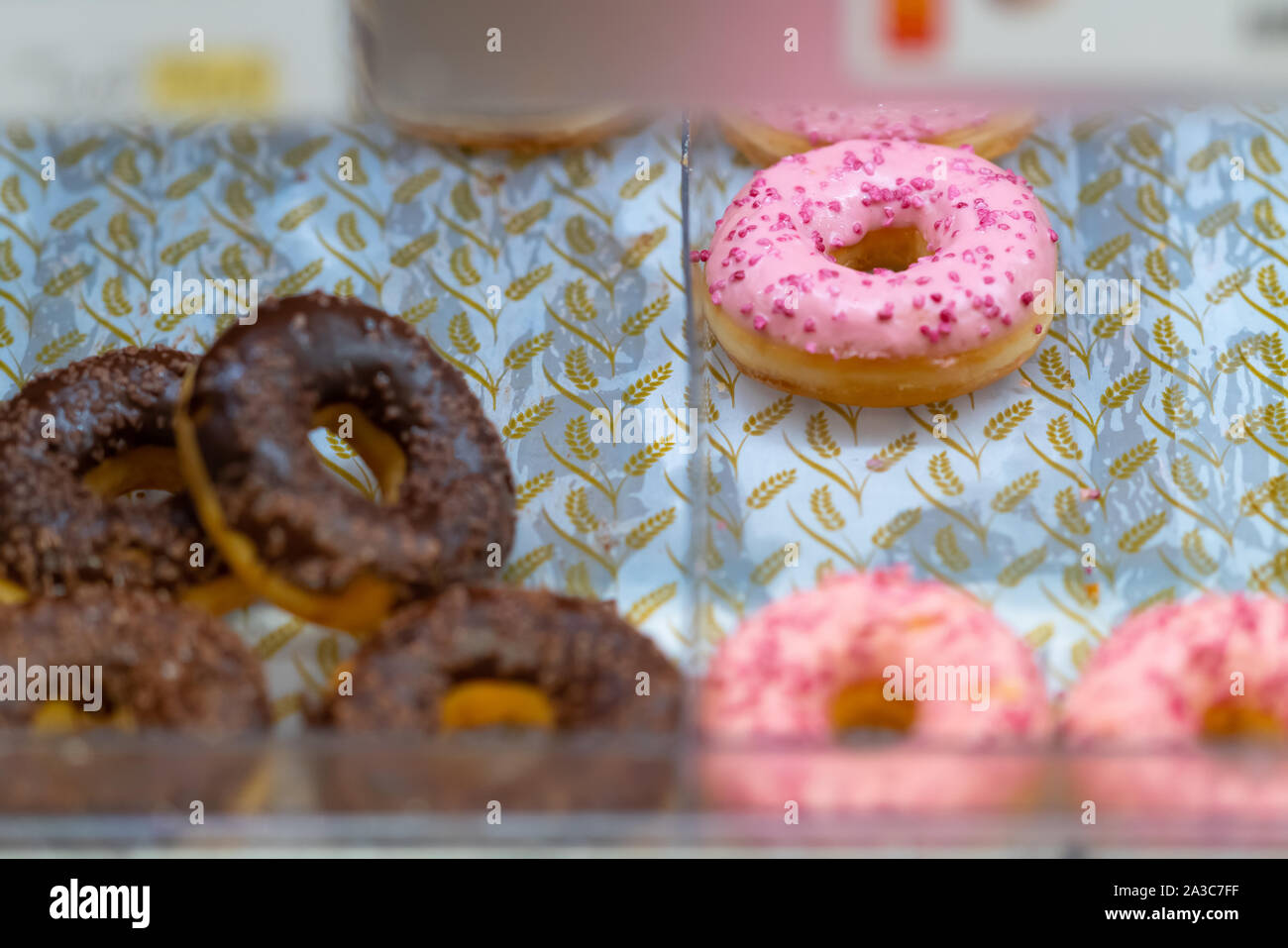 Assorted iced fresh donuts on display in a bakery or cafeteria counter ...