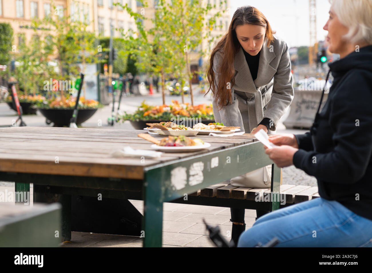 Two women sitting down for a meal outdoors at a cafeteria overlooking a ...