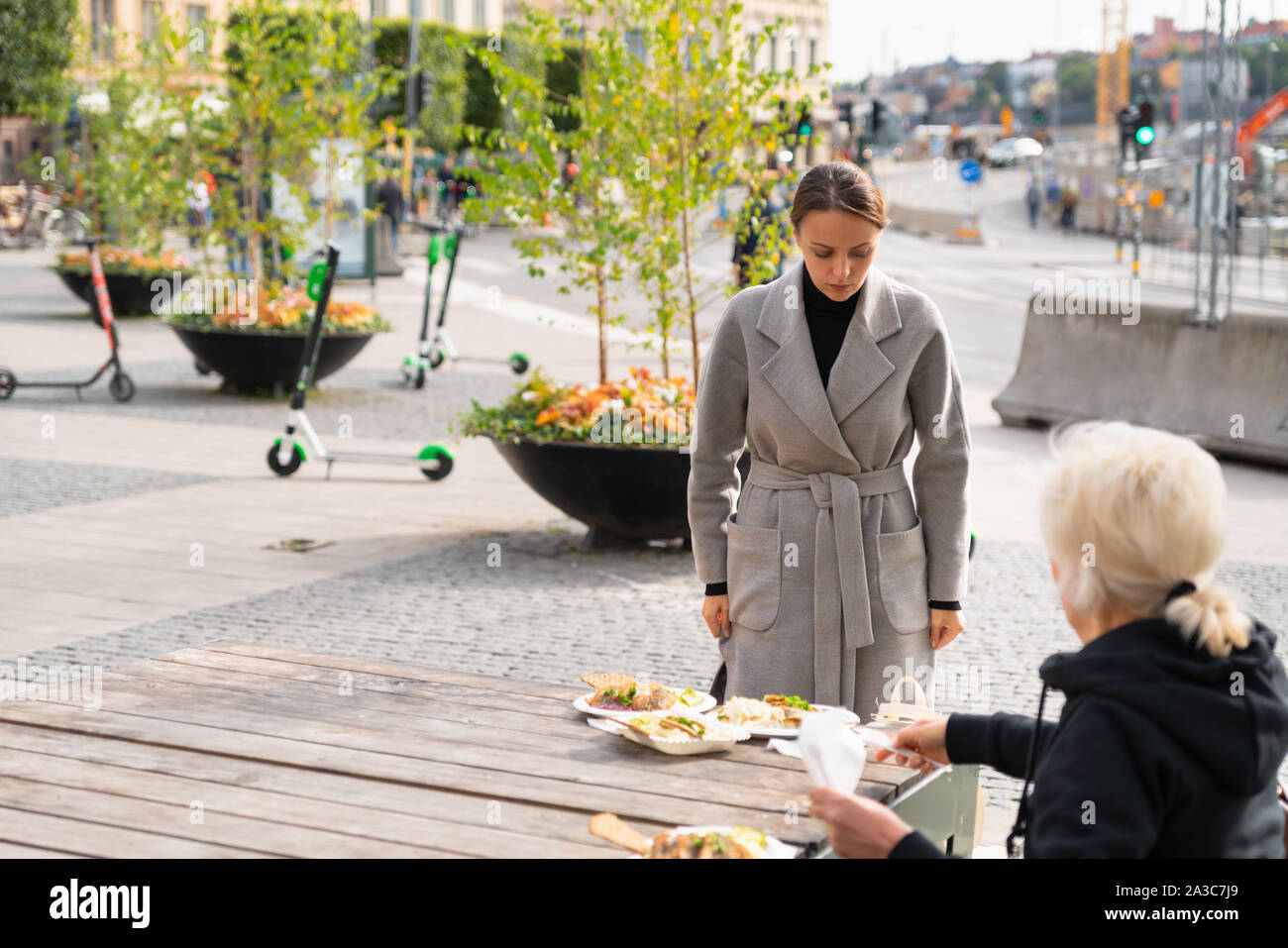 Young woman standing next to an outdoor table set with food at a ...