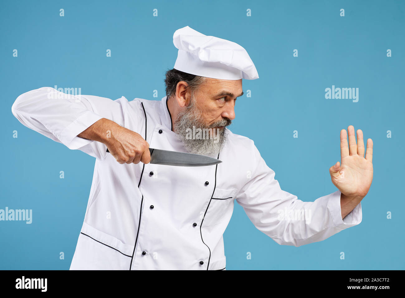 Side view portrait of charismatic bearded chef holding sharp knife ...