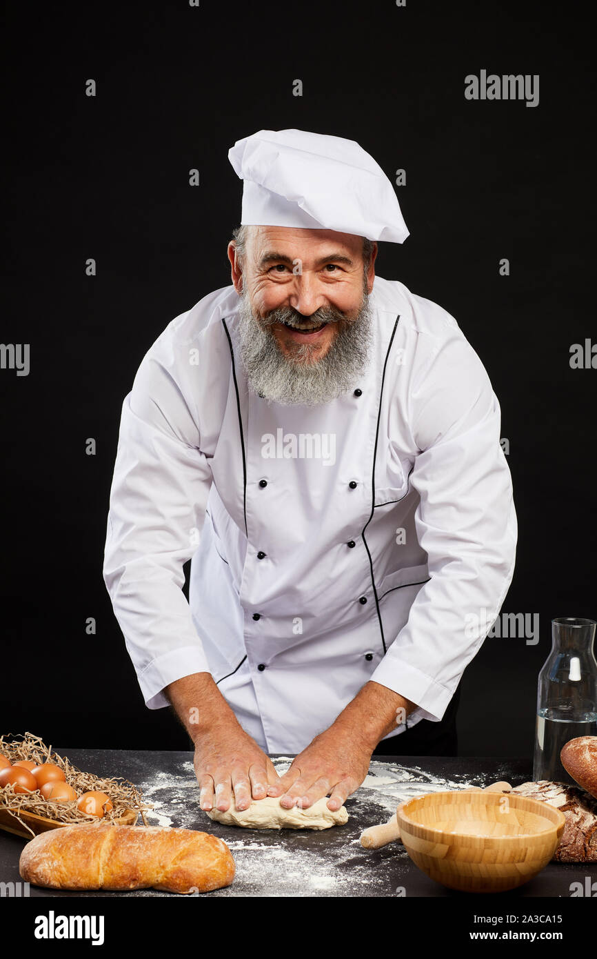 Portrait of charismatic bearded baker making fresh bred and smiling ...