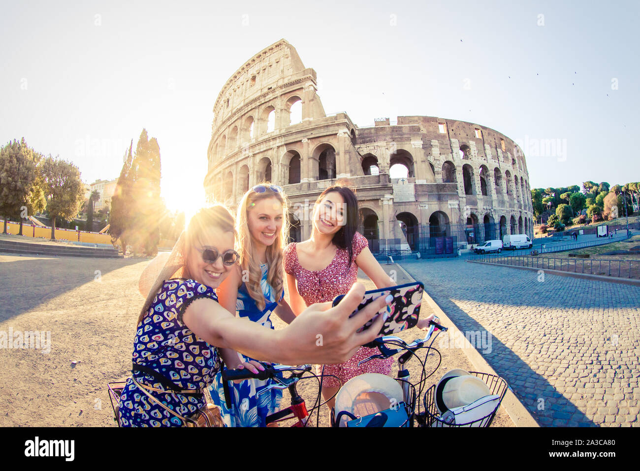 Three happy young women friends tourists with bikes taking selfies at ...