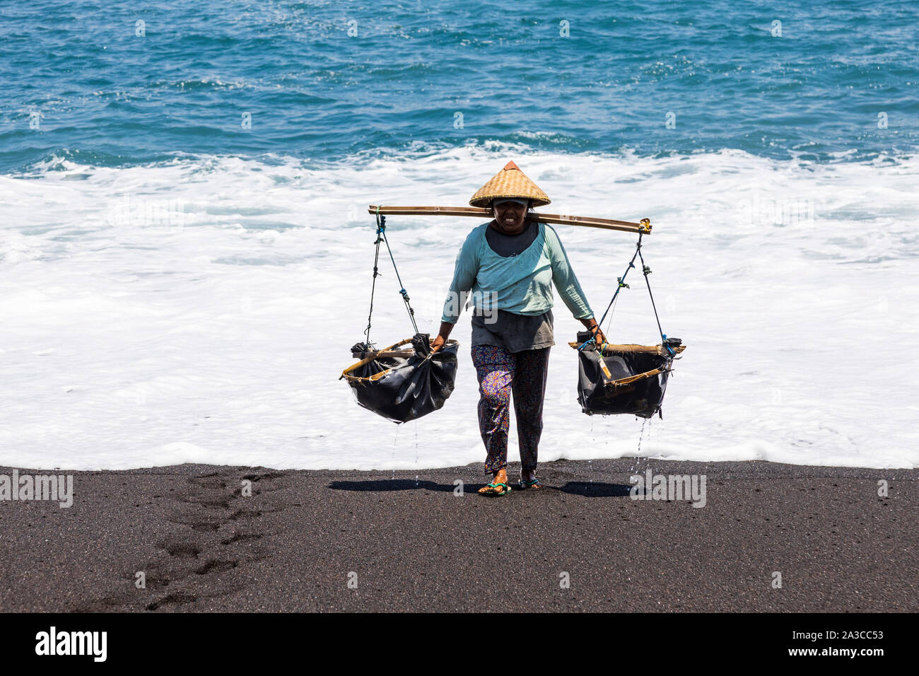 Woman gathering sea water to produce sea salt in Amuk Bay, Eastern Bali ...