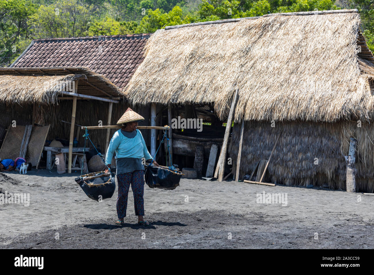 Woman gathering sea water to produce sea salt in Amuk Bay, Eastern Bali ...