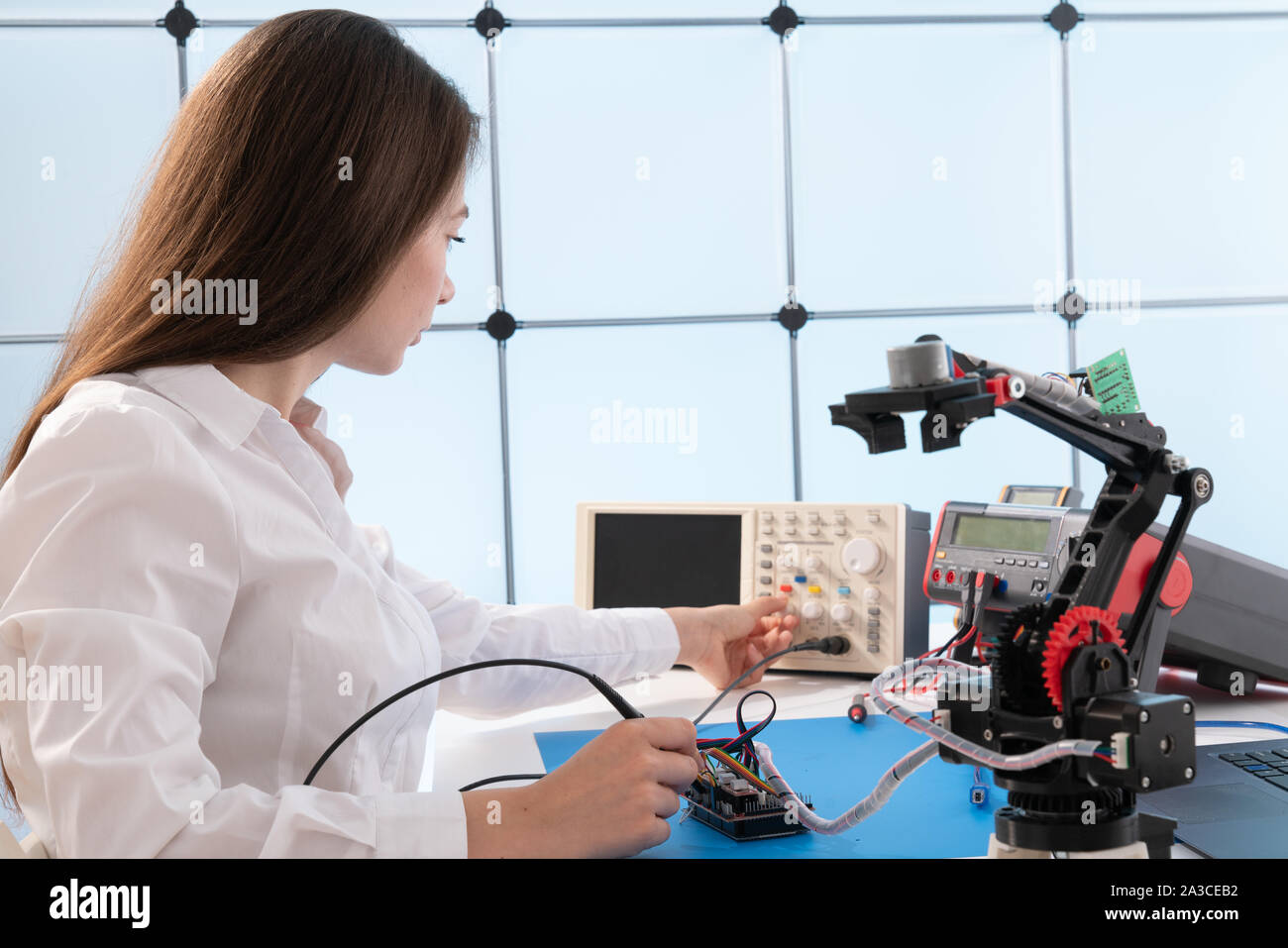 A young woman writes an algorithm for the robot arm. Science Research ...