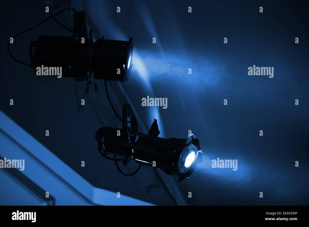 Two blue spot lights with smoky rays mounted in dark room, stage ...