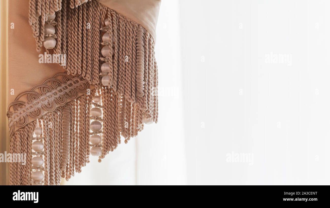Decorative luxury curtains fragment with fringe over white window ...