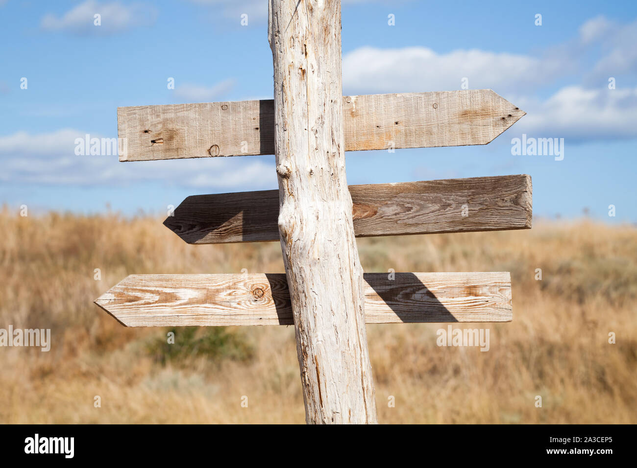 Rural empty wooden guidepost with arrow shaped planks over blue sky and ...