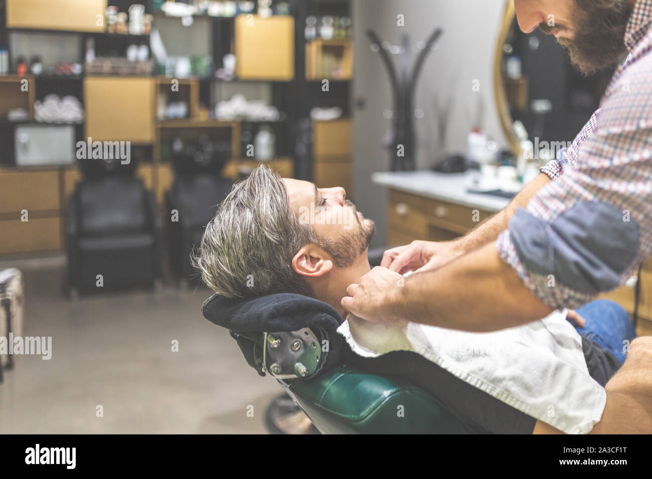 Hairdresser preparing client for shaving with towel. Man visiting ...
