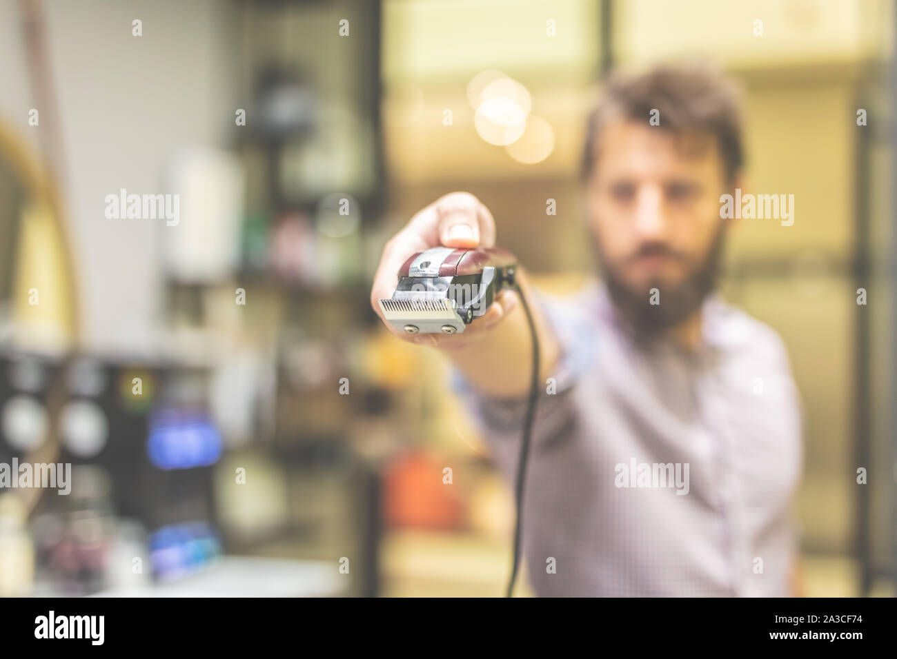 Modern barber holding hair clipper at barbershop Stock Photo - Alamy