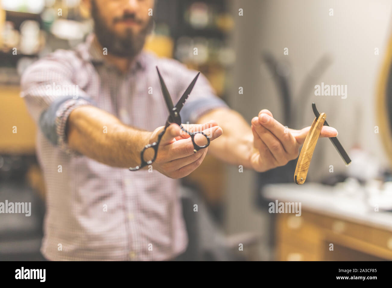 Modern barber holding scissors and razor at barbershop Stock Photo - Alamy