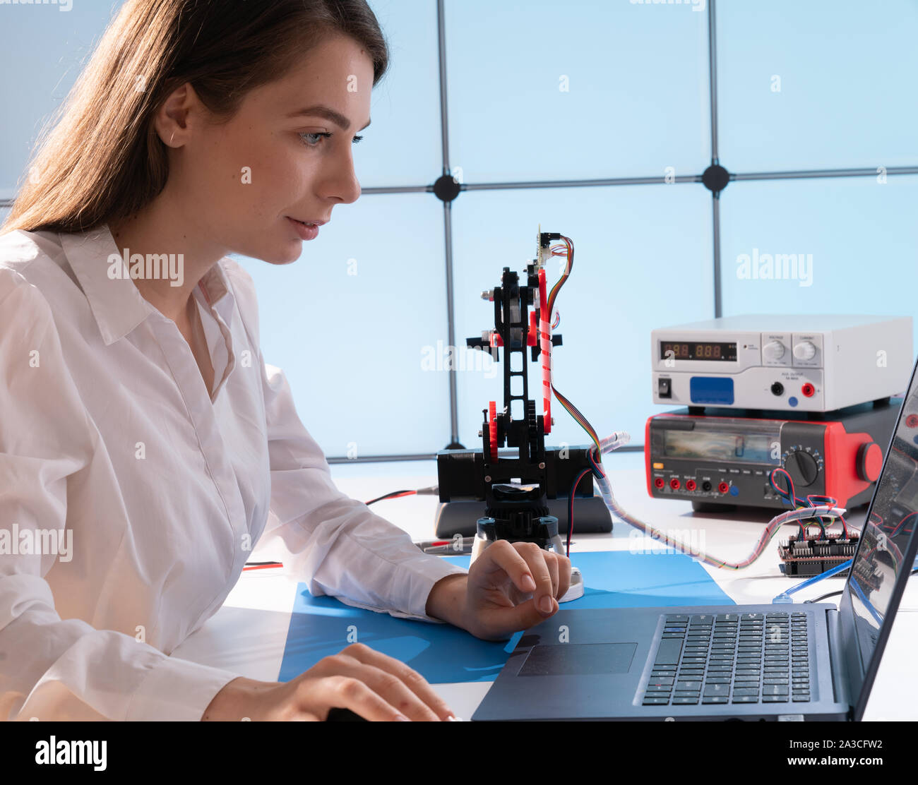 A young woman writes an algorithm for the robot arm. Science Research ...