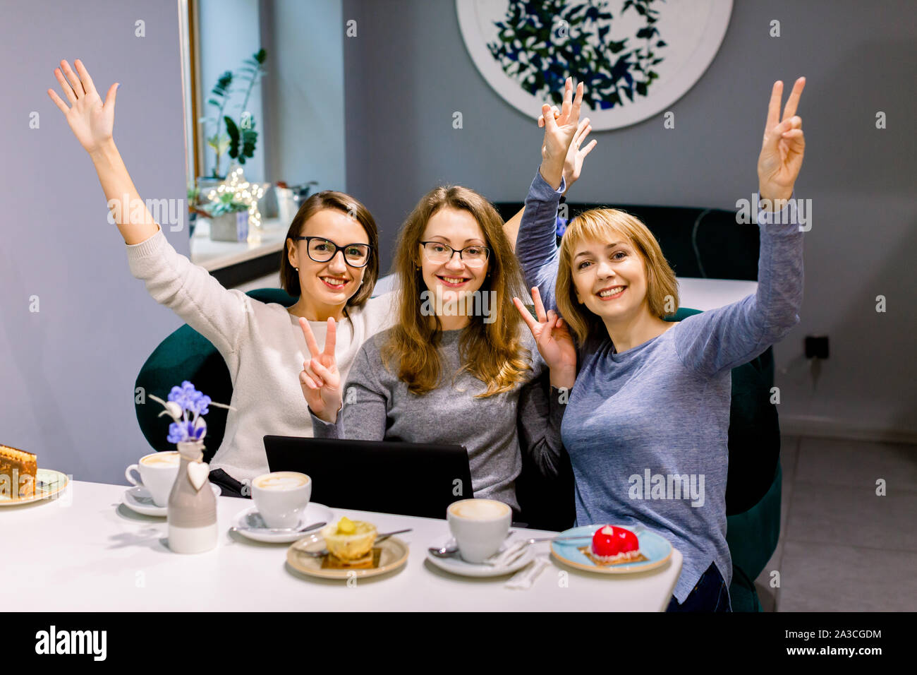 Three female pretty friends with hands up having fun and eating ...