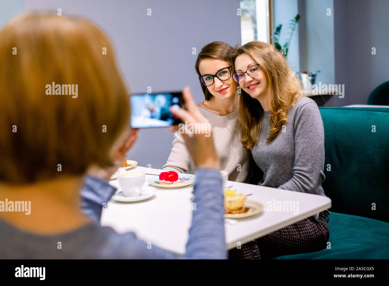 Women friends in cafe indoors. Two pretty women friends hugging and ...