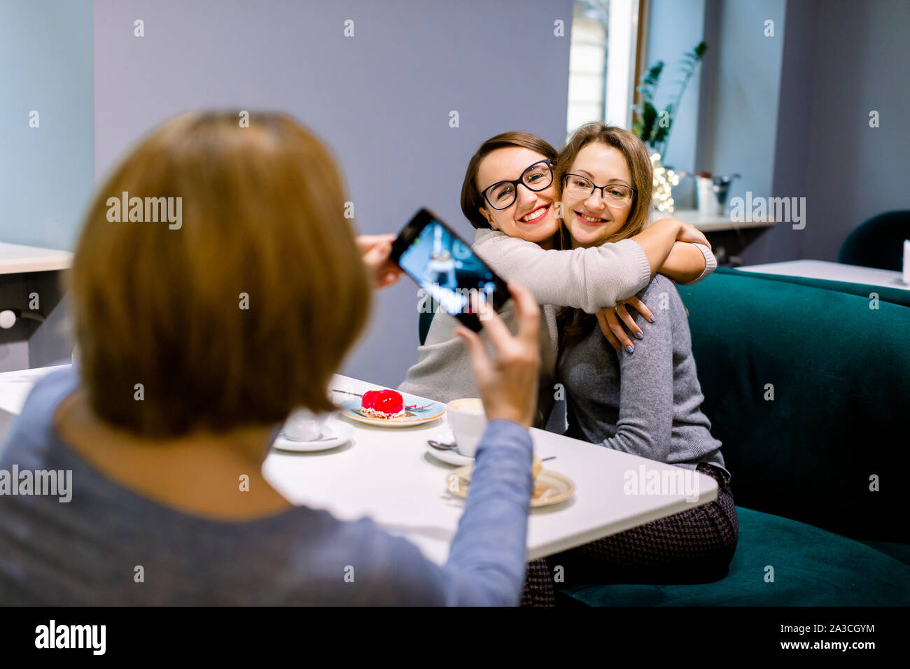 Women friends in cafe indoors. Two pretty women friends hugging and ...