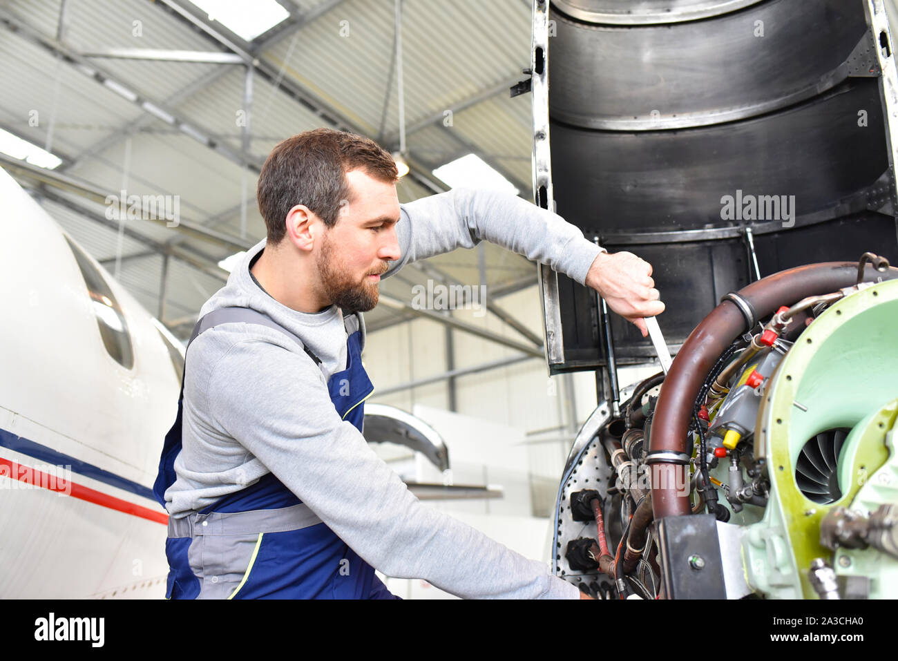 Aircraft mechanic repairs an aircraft engine in an airport hangar Stock ...