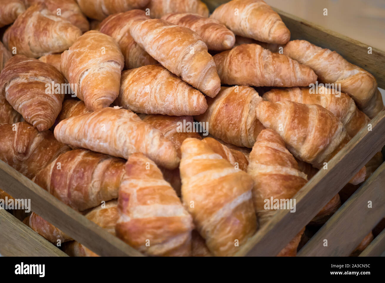 Croissants in an open wooden box. Freshly baked croissants in wooden ...