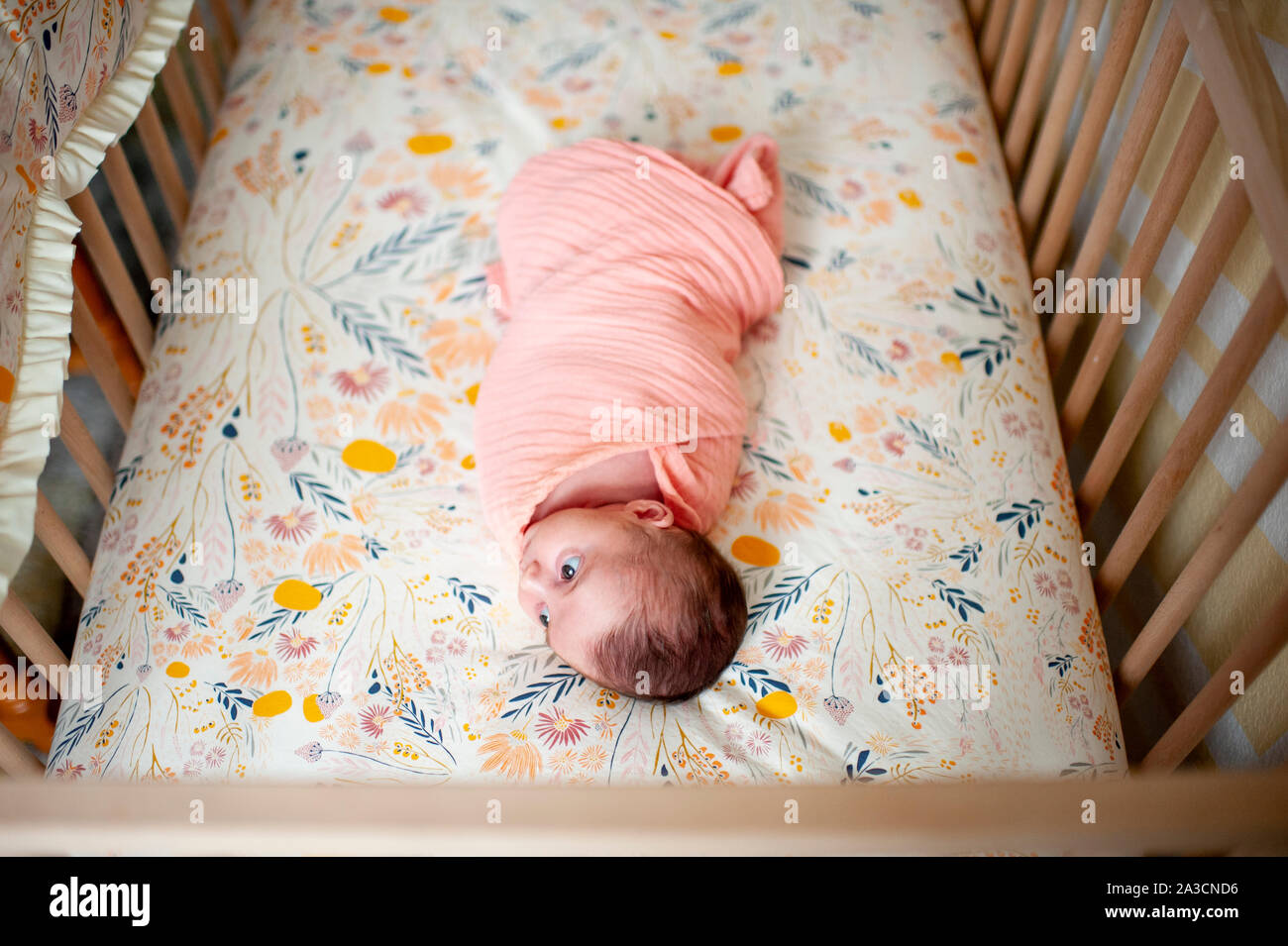 High angle view of newborn girl in crib with eyes open at home Stock ...