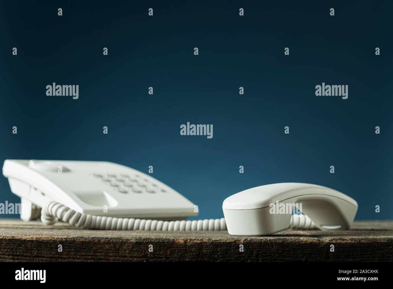 Low angle view of white landline telephone with handset off the hook on ...