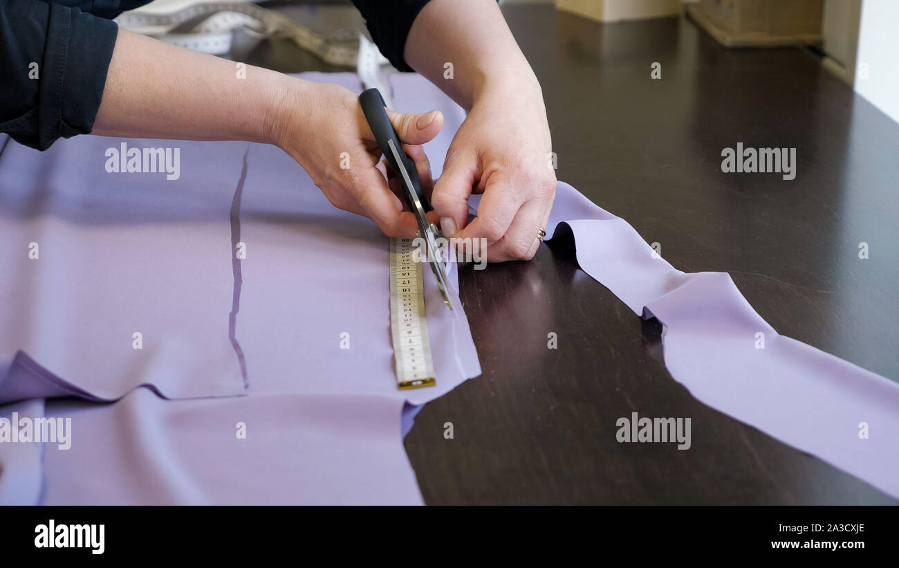 Cutting and sewing products in tailoring business. Tailor woman cutting ...