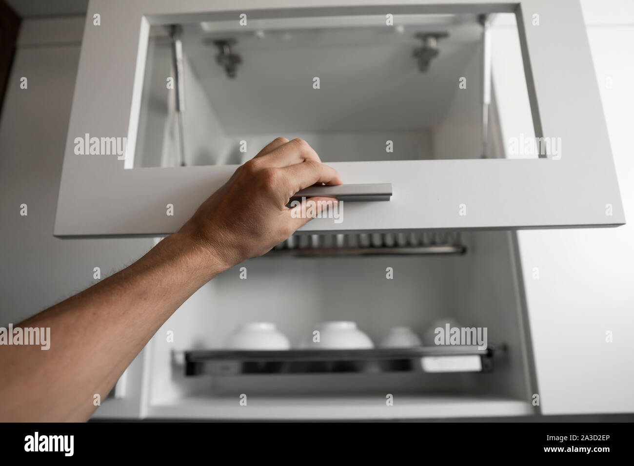 Hand holds the door of the dryer with utensils. Dish drying metal rack ...