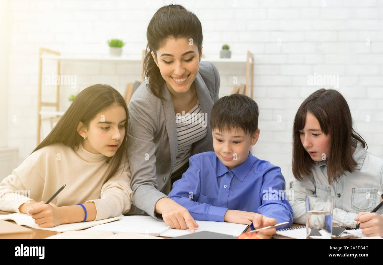 Young teacher helping children doing homework together Stock Photo - Alamy