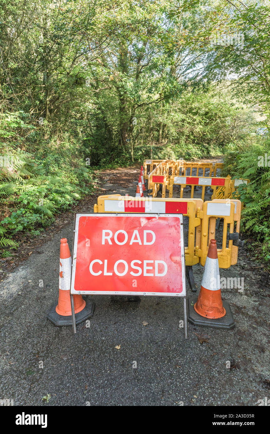 Red Road Closed warning sign in country road lane, along with traffic ...