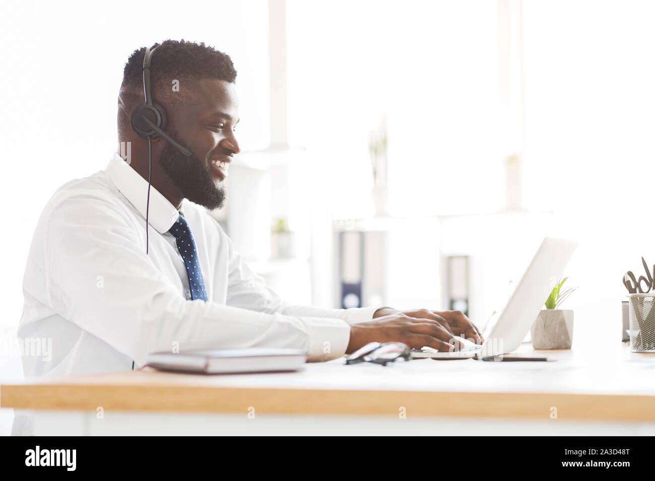 Side view of young customer service agent working in office Stock Photo ...