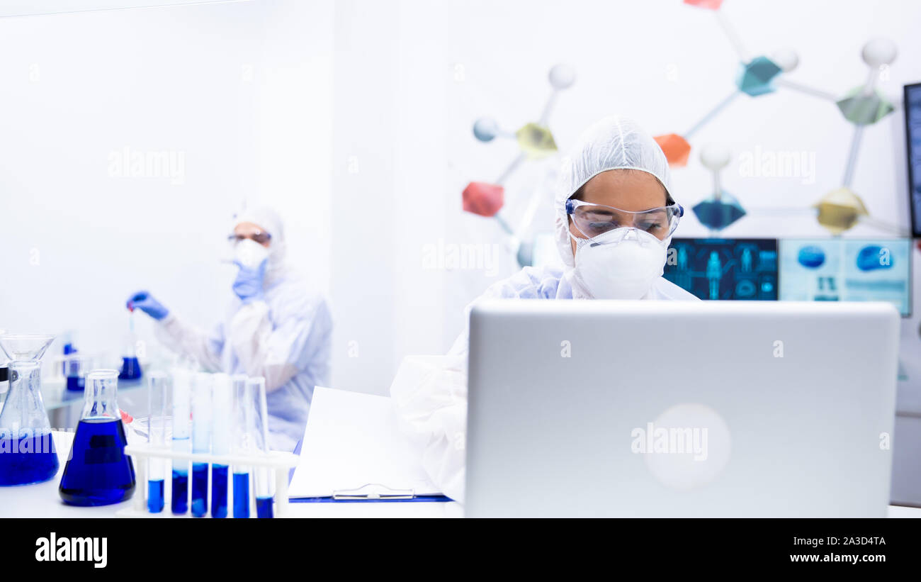 Scientist woman working on laptop in the laboratory. Surrounded by ...