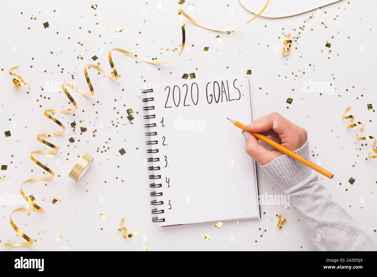 Woman writing down in notepad with 2020 goals Stock Photo - Alamy