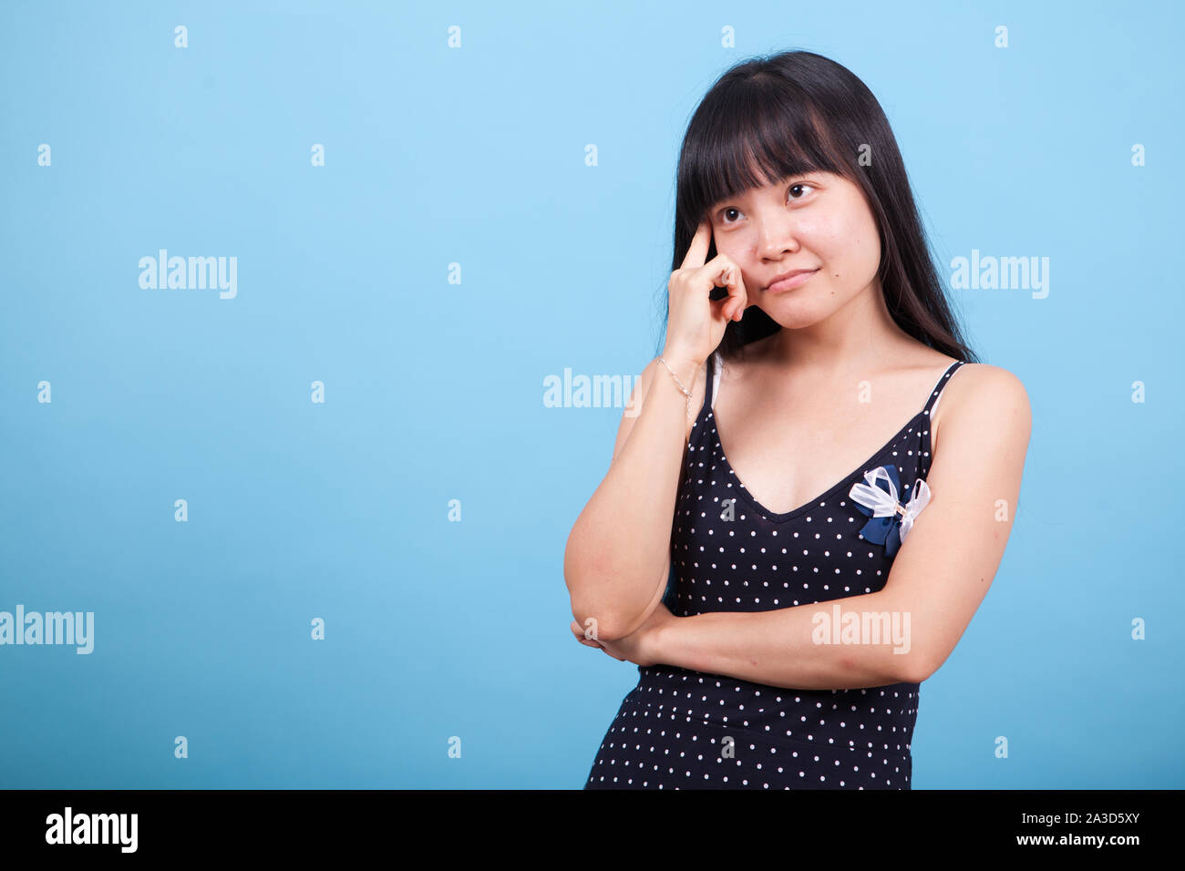 Portrait of thoughtful asian girl in studio over blue background. Asian ...
