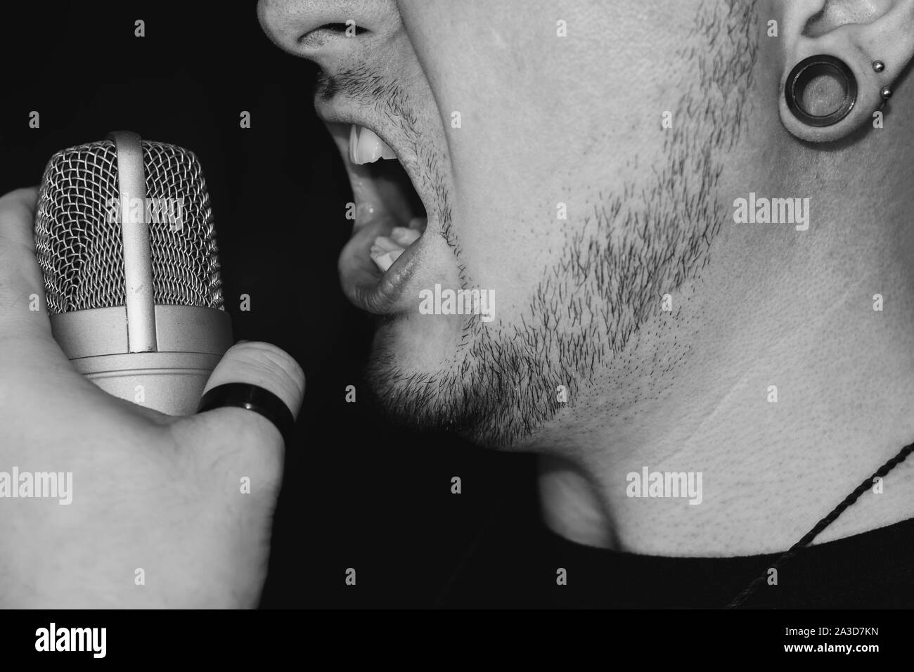 Man screaming on the microphone. Singing heavy metal. Close-up on a man ...