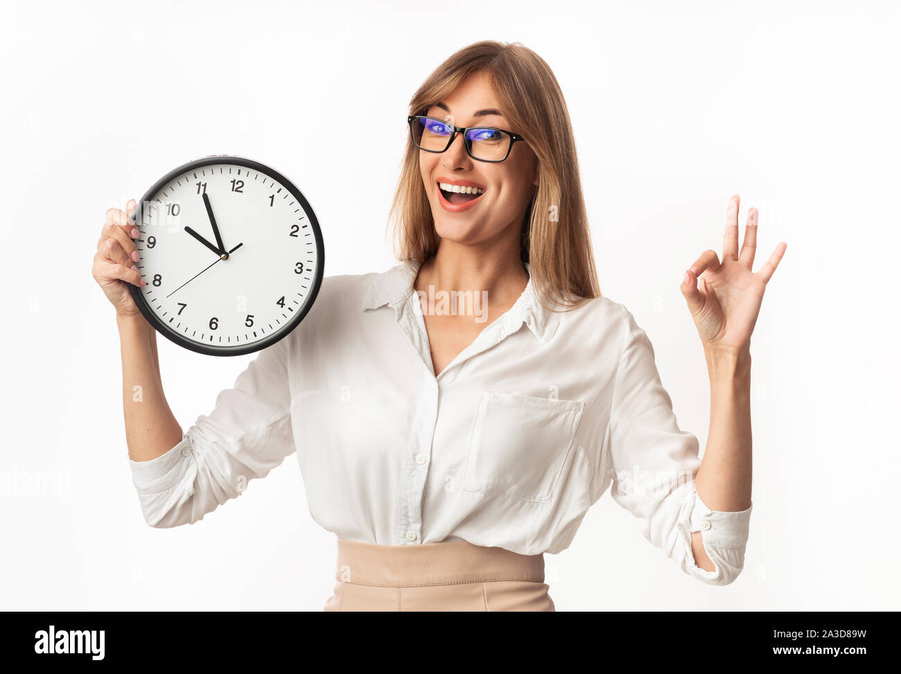 Happy Businesswoman Holding Clock Gesturing OK Standing On White ...
