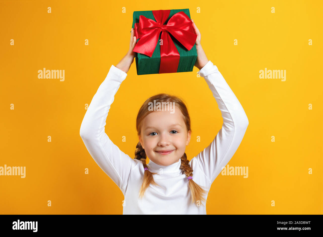 Cute happy little girl holding a box with a gift over her head. A child ...