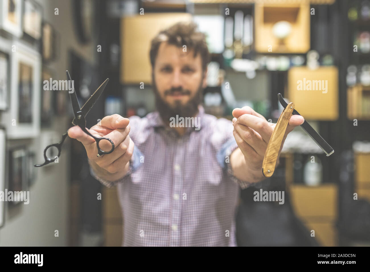 Modern barber holding scissors and razor at barbershop Stock Photo - Alamy