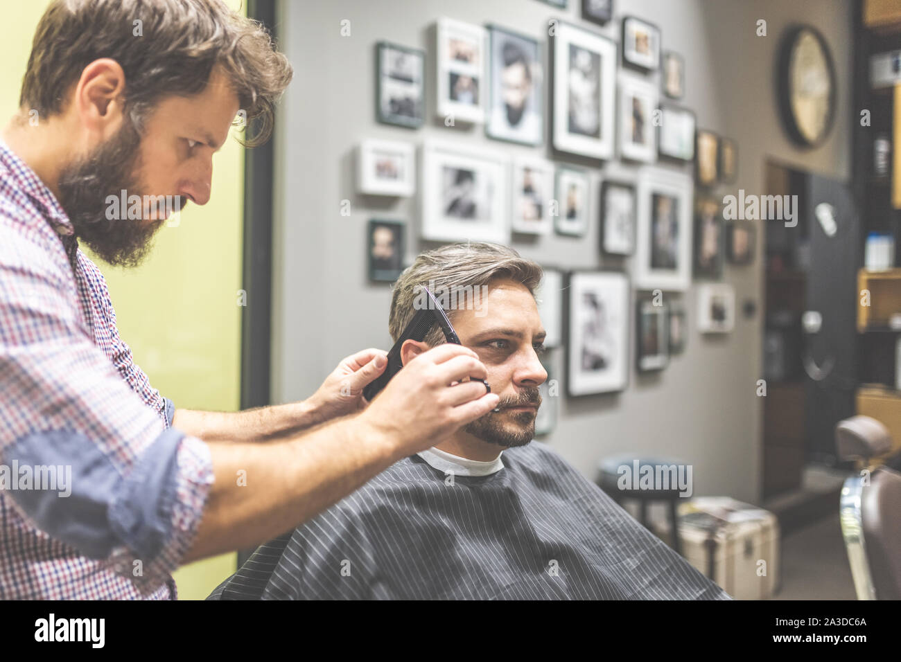 Barber cutting and modeling hair with scissors and comb Stock Photo - Alamy
