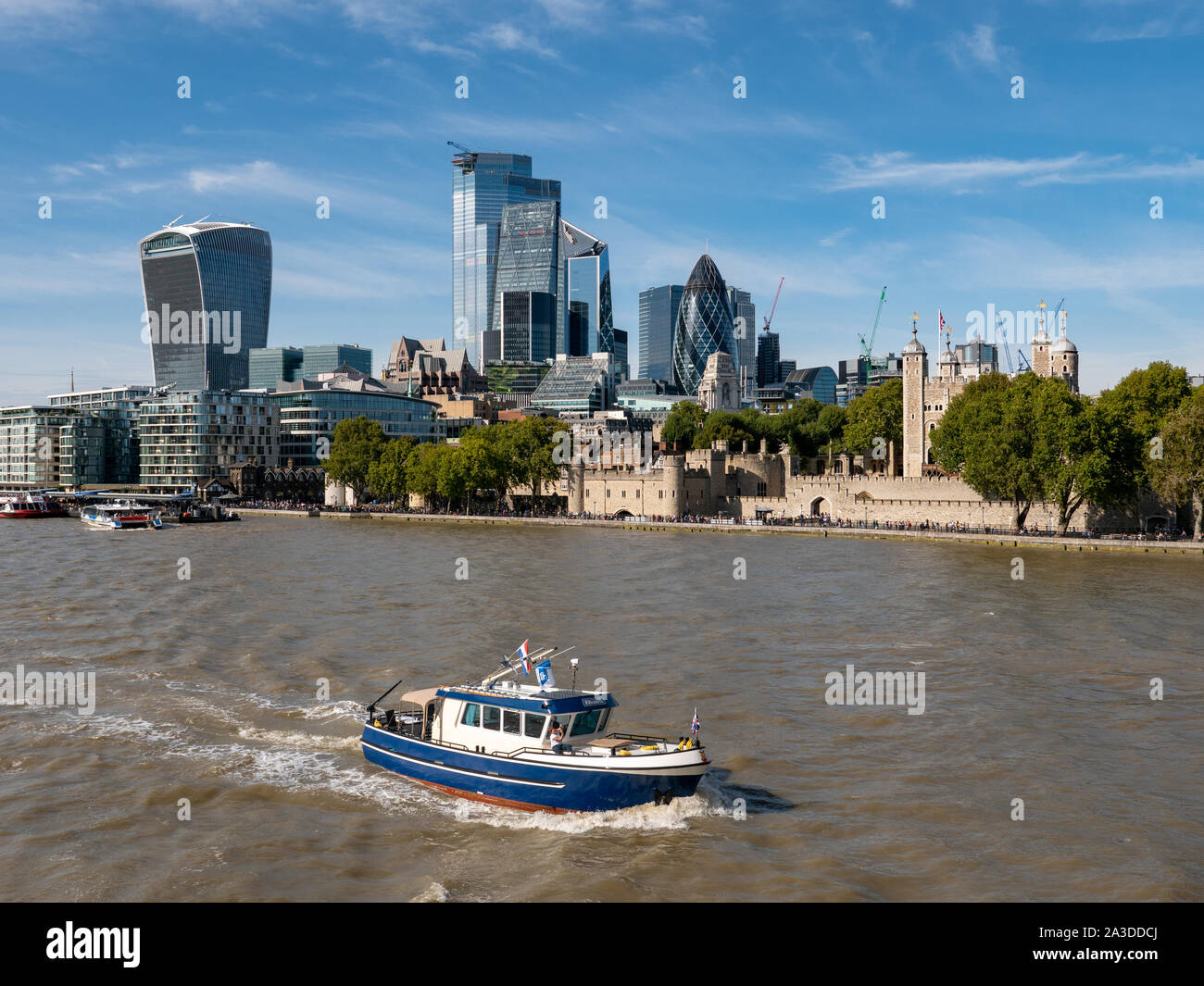 Small boat on the river Thames with City of London skyscrapers behind ...